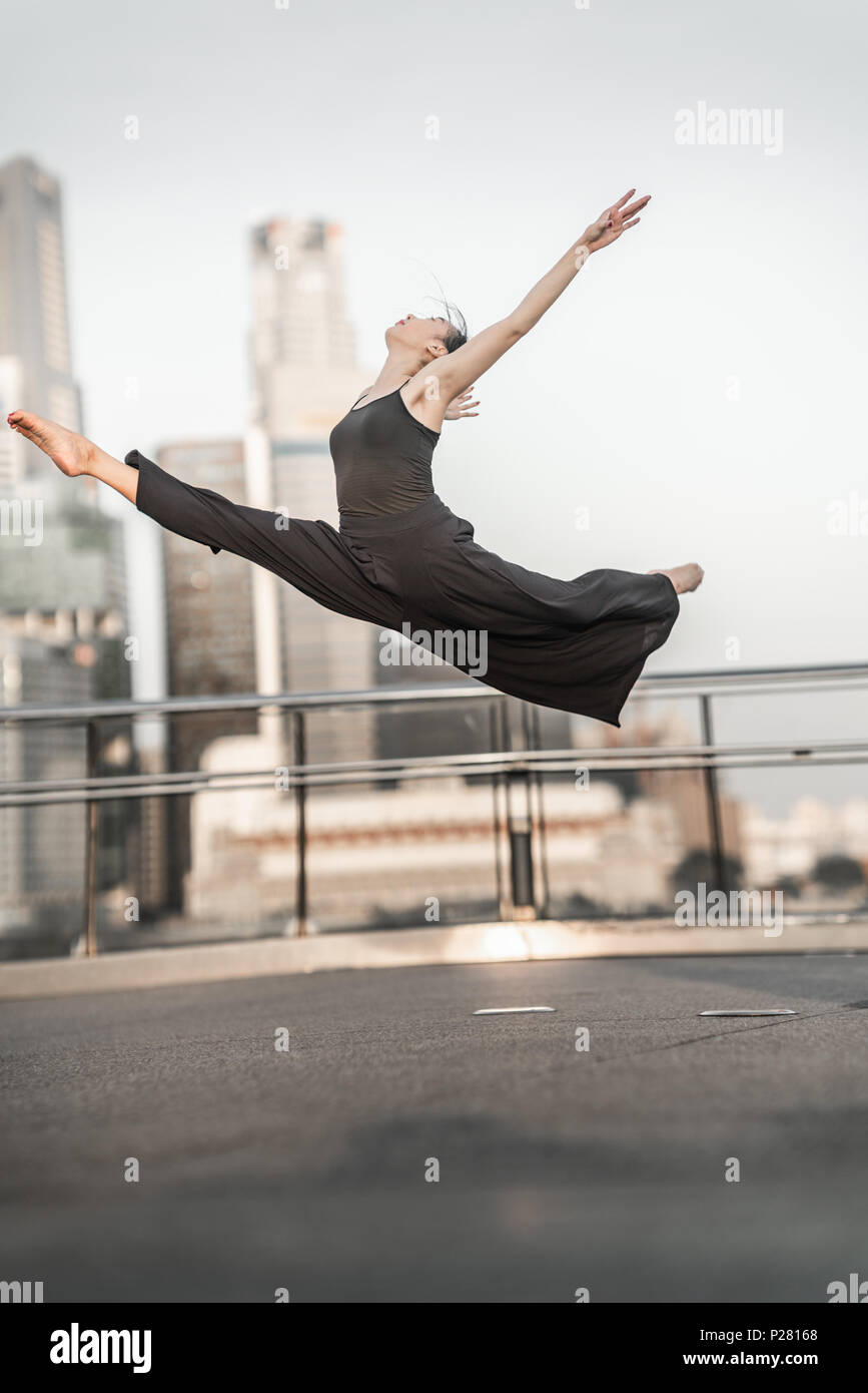 Cute Young woman athlete performs a perfect straddle leap high up, with ...