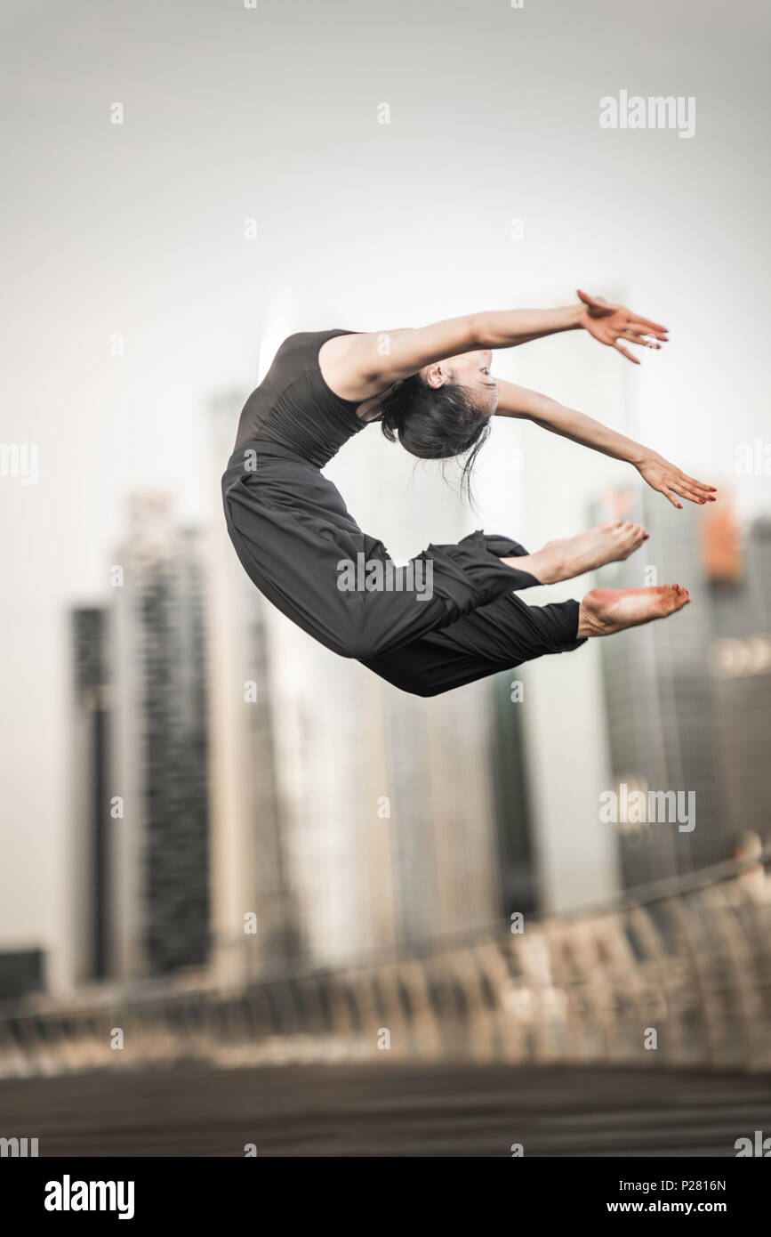 Cute Young woman athlete performs a perfect straddle leap high up, with ...