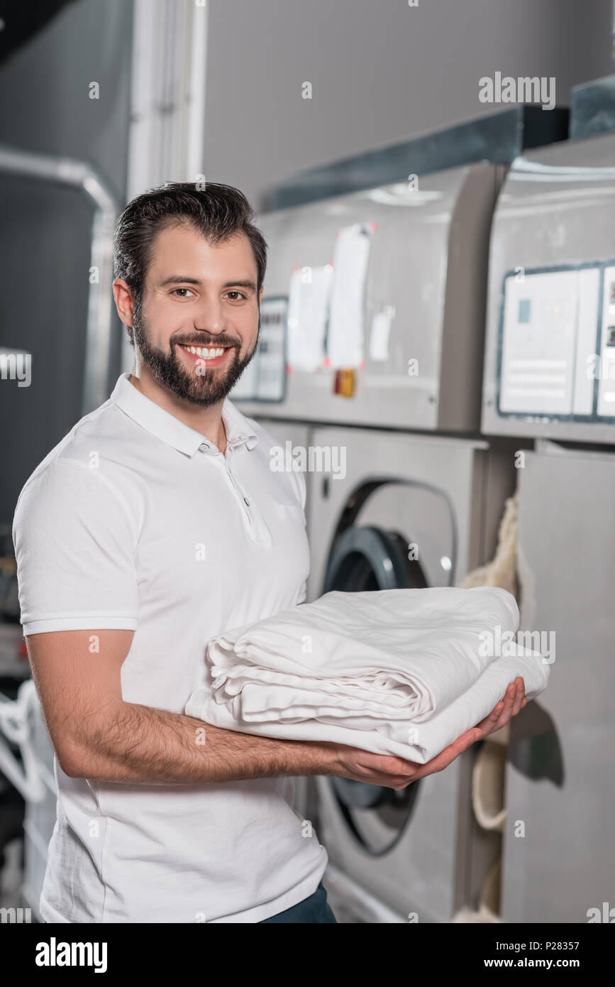 dry cleaning worker holding stack of clean clothes Stock Photo - Alamy