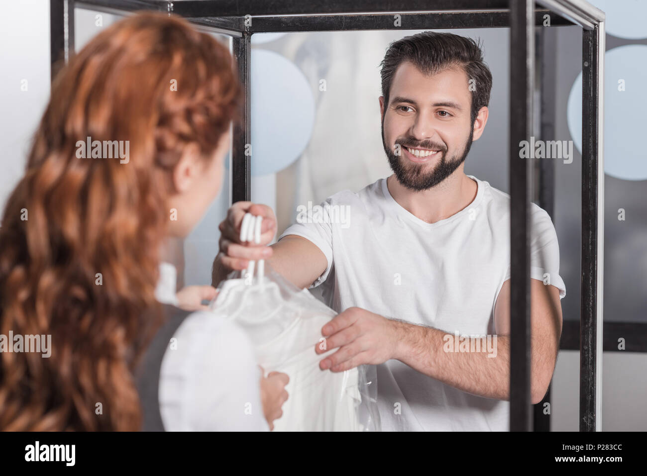 dry cleaning manager giving clothes to customer Stock Photo - Alamy