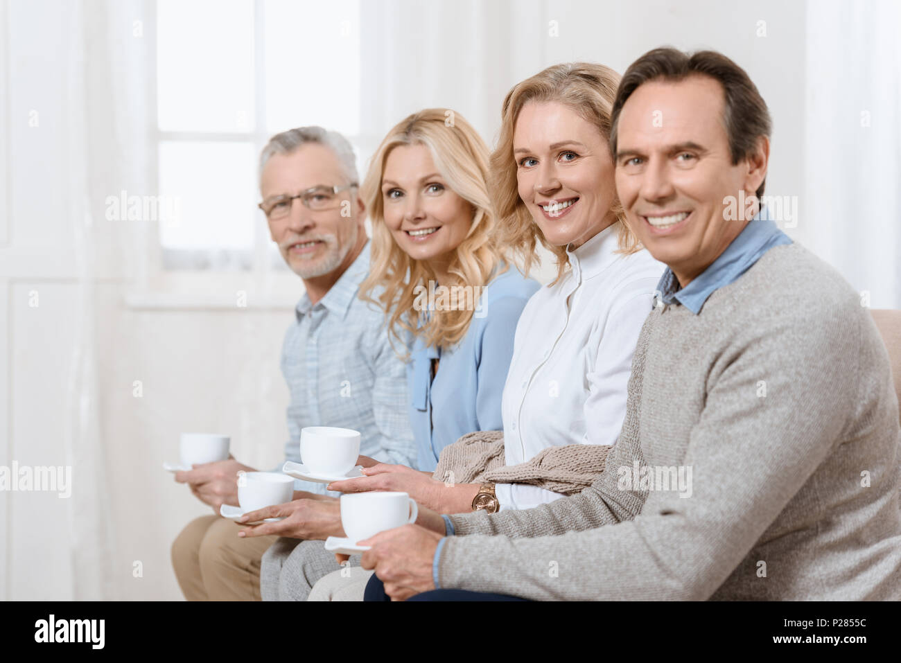 Middle aged men and women having a conversation while drinking tea on ...