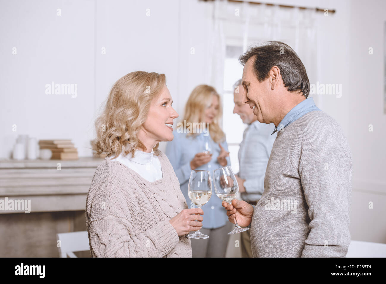 happy friends speaking and holding glasses in hands in room Stock Photo ...