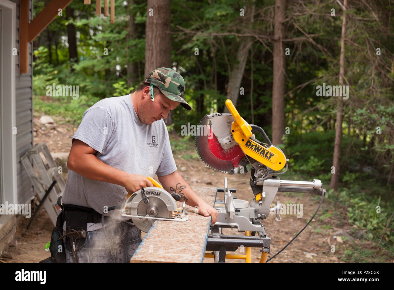 A construction worker using a handheld circular saw to cut a wooden ...