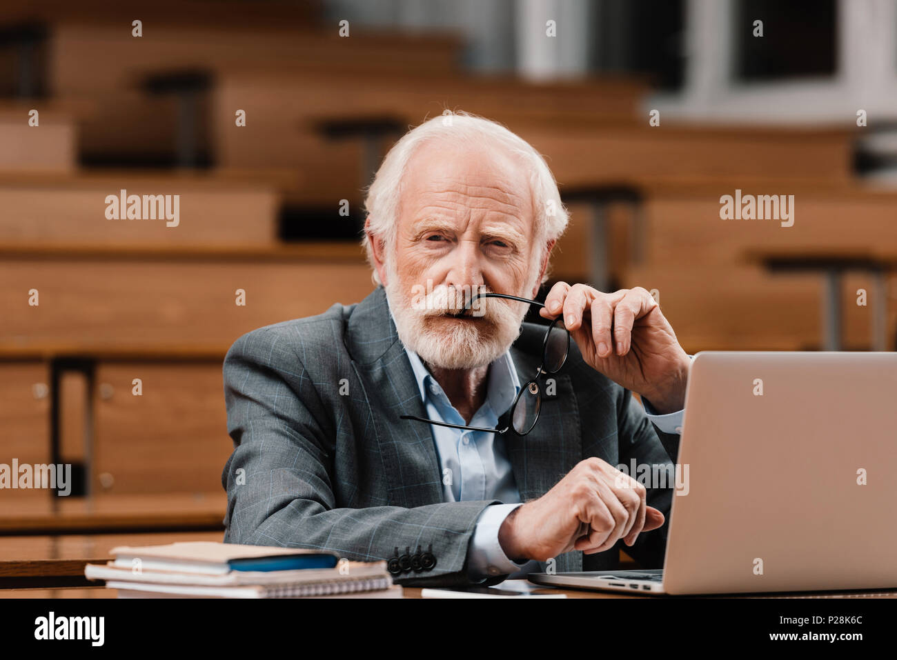 grey hair professor holding eyeglasses and looking at camera Stock ...