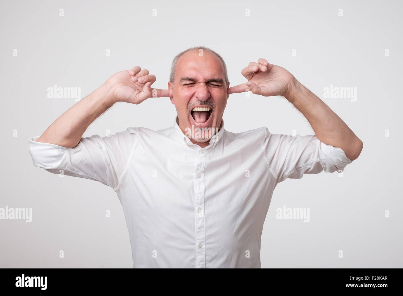 Mature european man closing his ears because of loud sound and noise. I ...