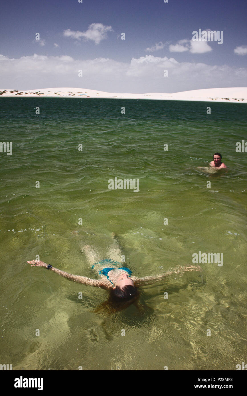 A woman floats in a lagoon surrounded by sand dunes in northeast Brazil ...
