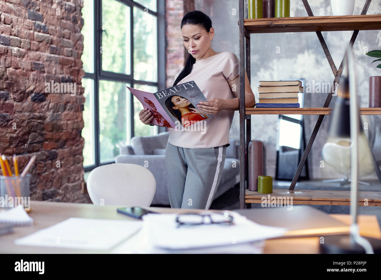 Focused female employee reading magazine Stock Photo - Alamy