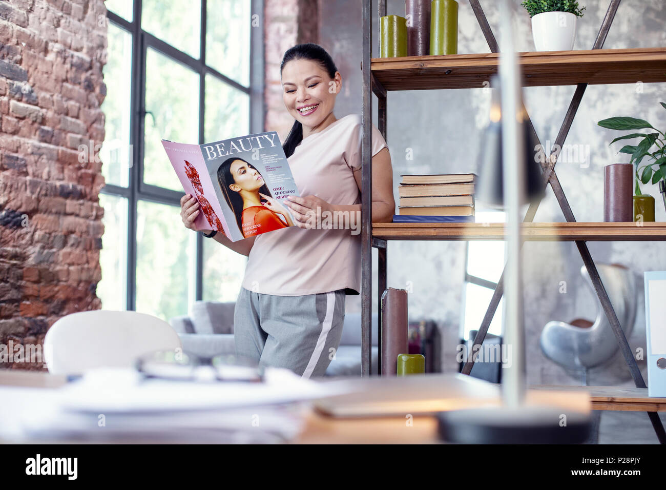 Happy female employee studying magazine Stock Photo - Alamy