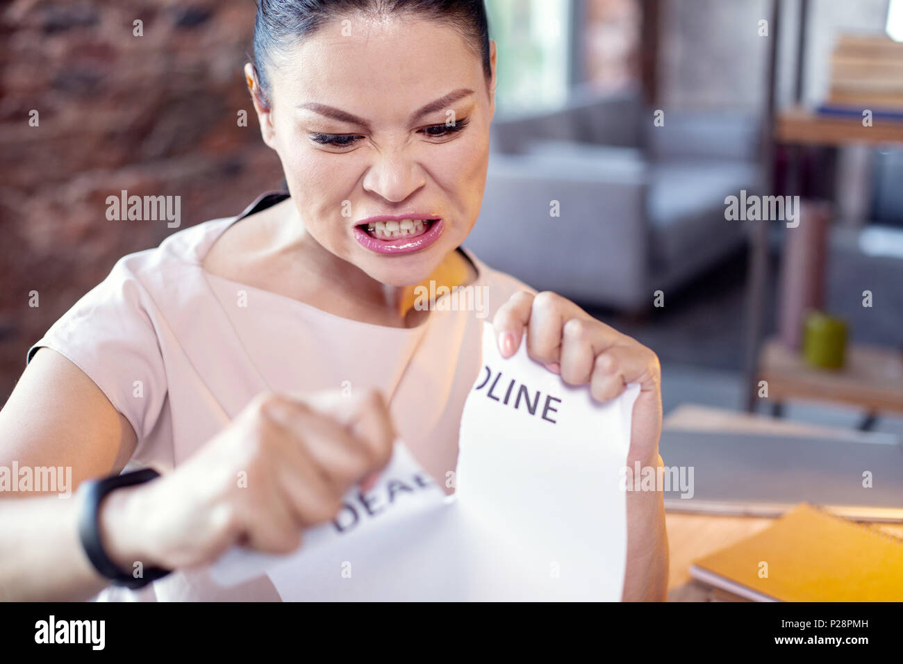 Grumpy female employee ripping apart paper Stock Photo - Alamy