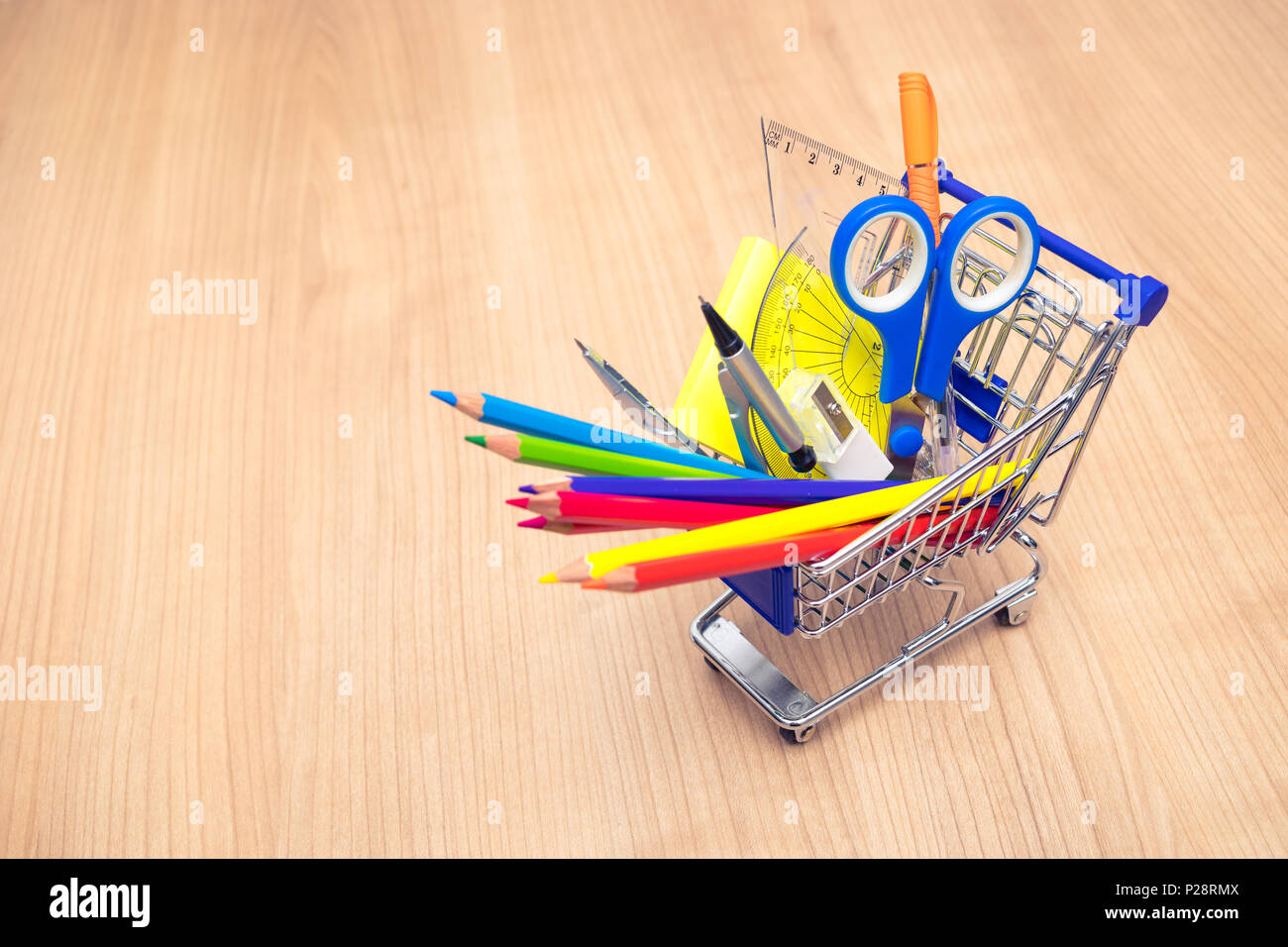 Shopping cart with school supplies on table . Back to school concept ...