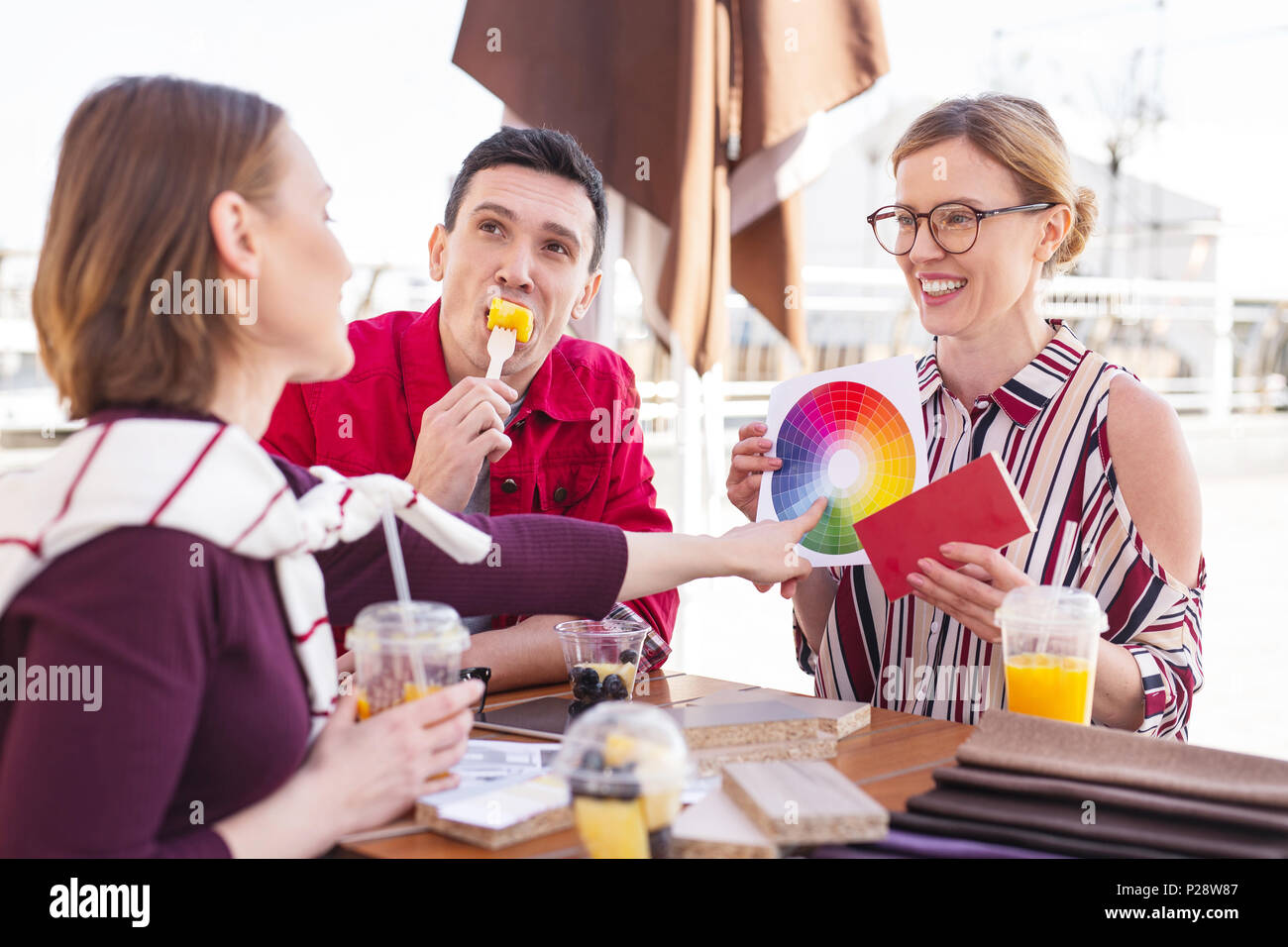 Dark-haired man eating mango sitting outside with friends Stock Photo ...