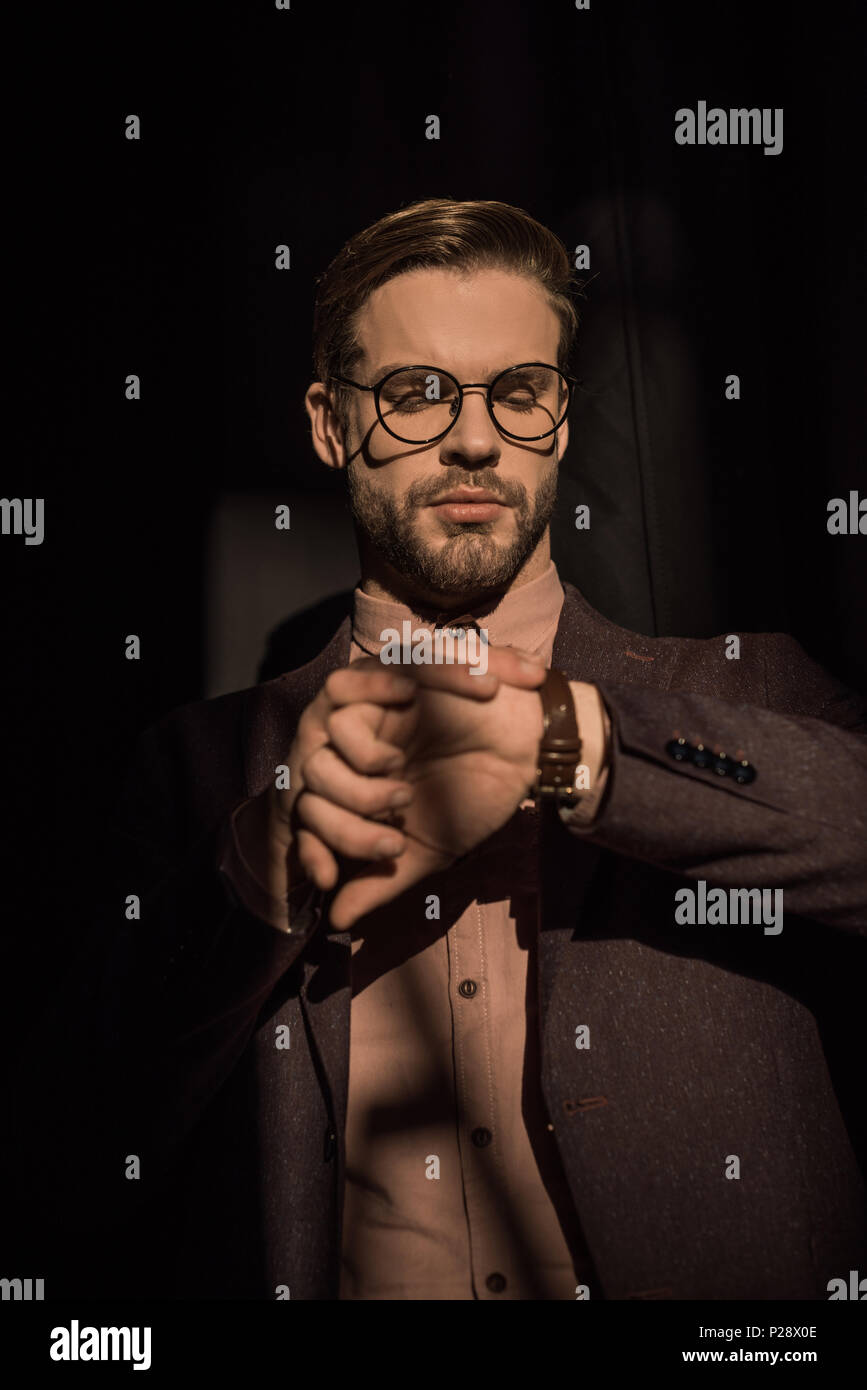 portrait of handsome stylish man in spectacles checking wristwatch ...