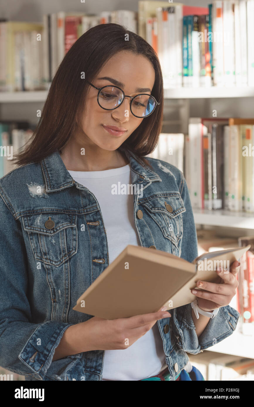 african american girl reading book in library Stock Photo - Alamy
