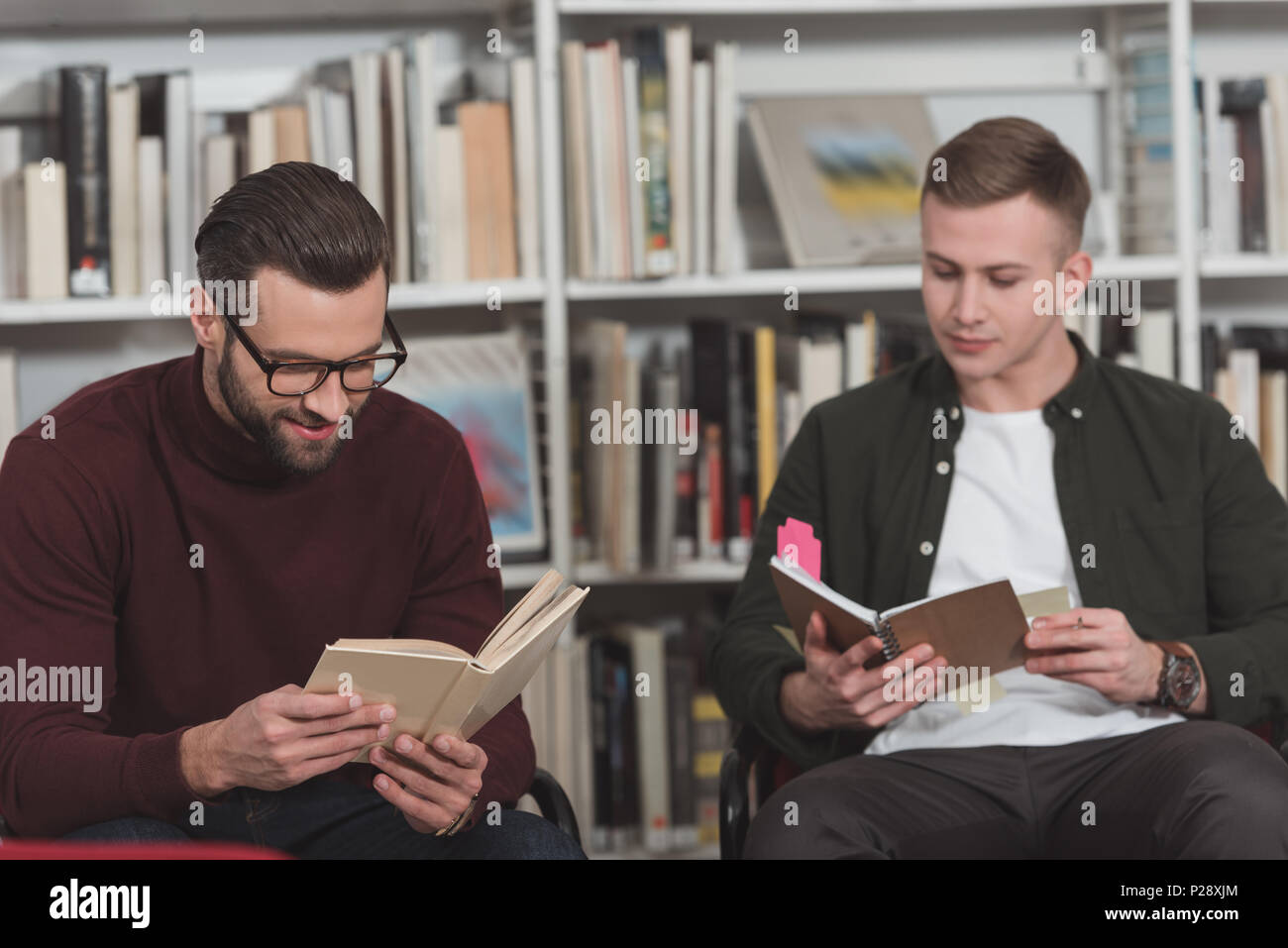 handsome men sitting with books in library Stock Photo - Alamy