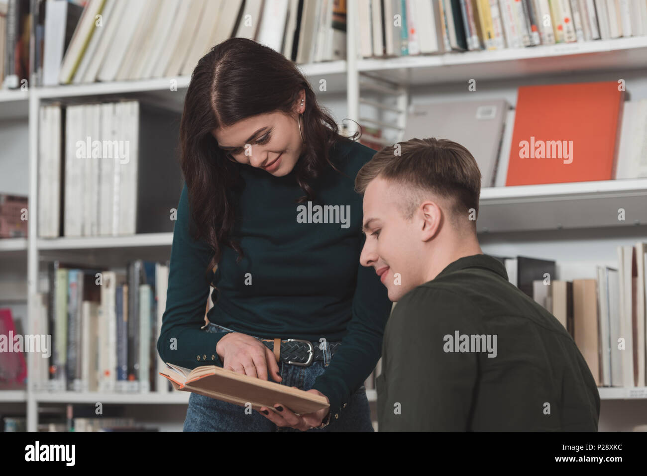 girl showing something in book to friend in library Stock Photo - Alamy