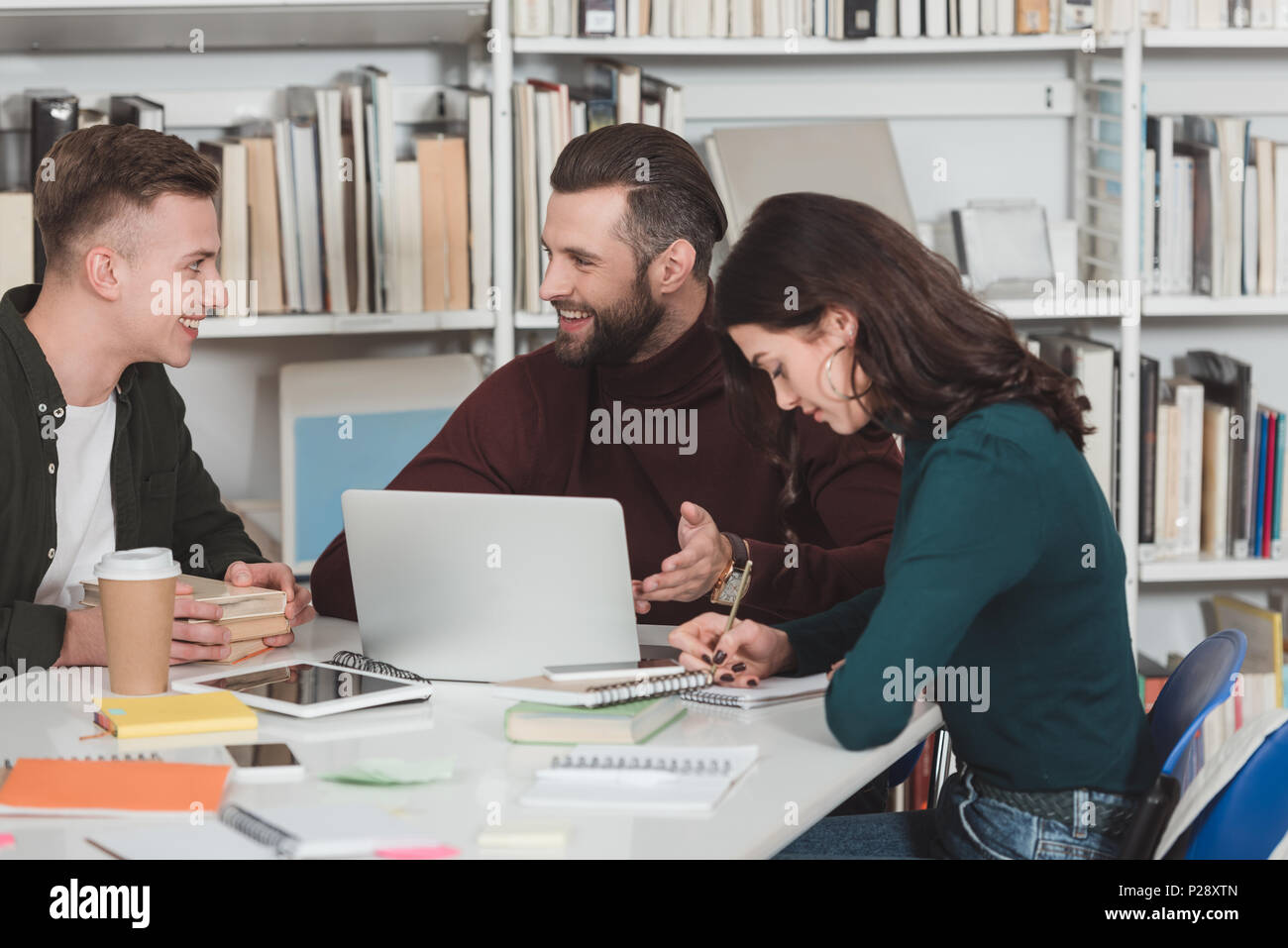 three students studying with laptop in library Stock Photo - Alamy