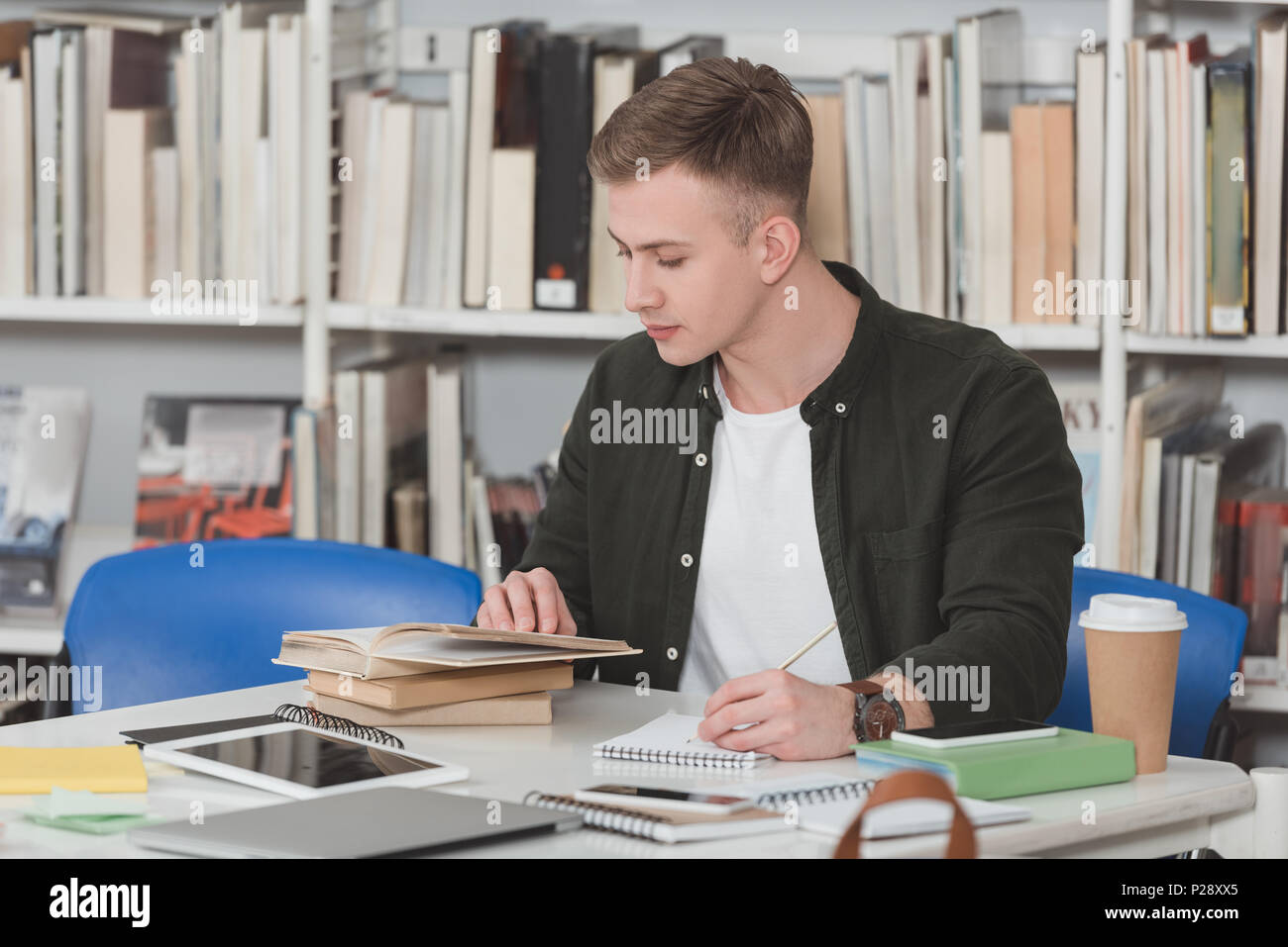 student reading book and making notes in library Stock Photo - Alamy