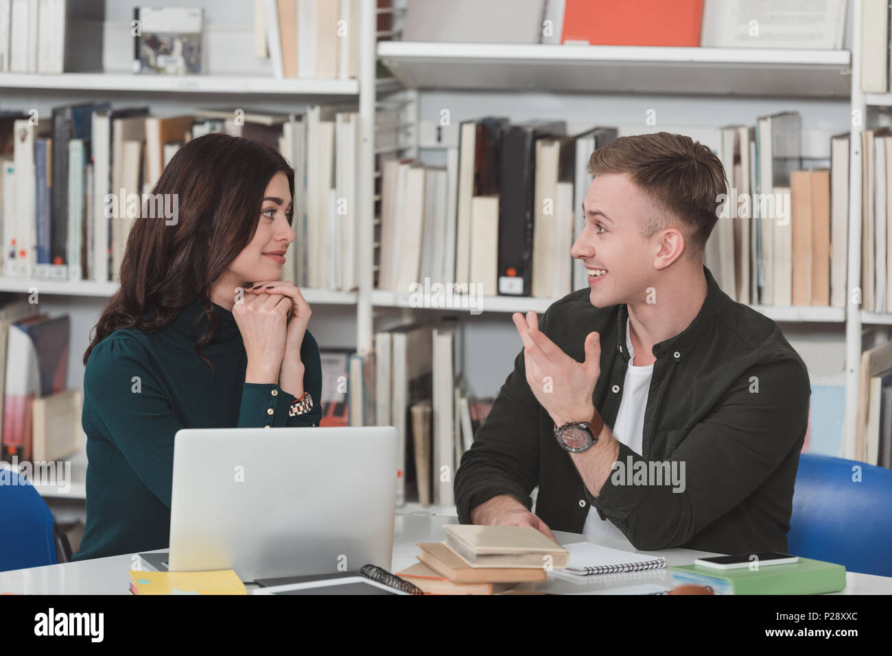 smiling students talking at table in library Stock Photo - Alamy