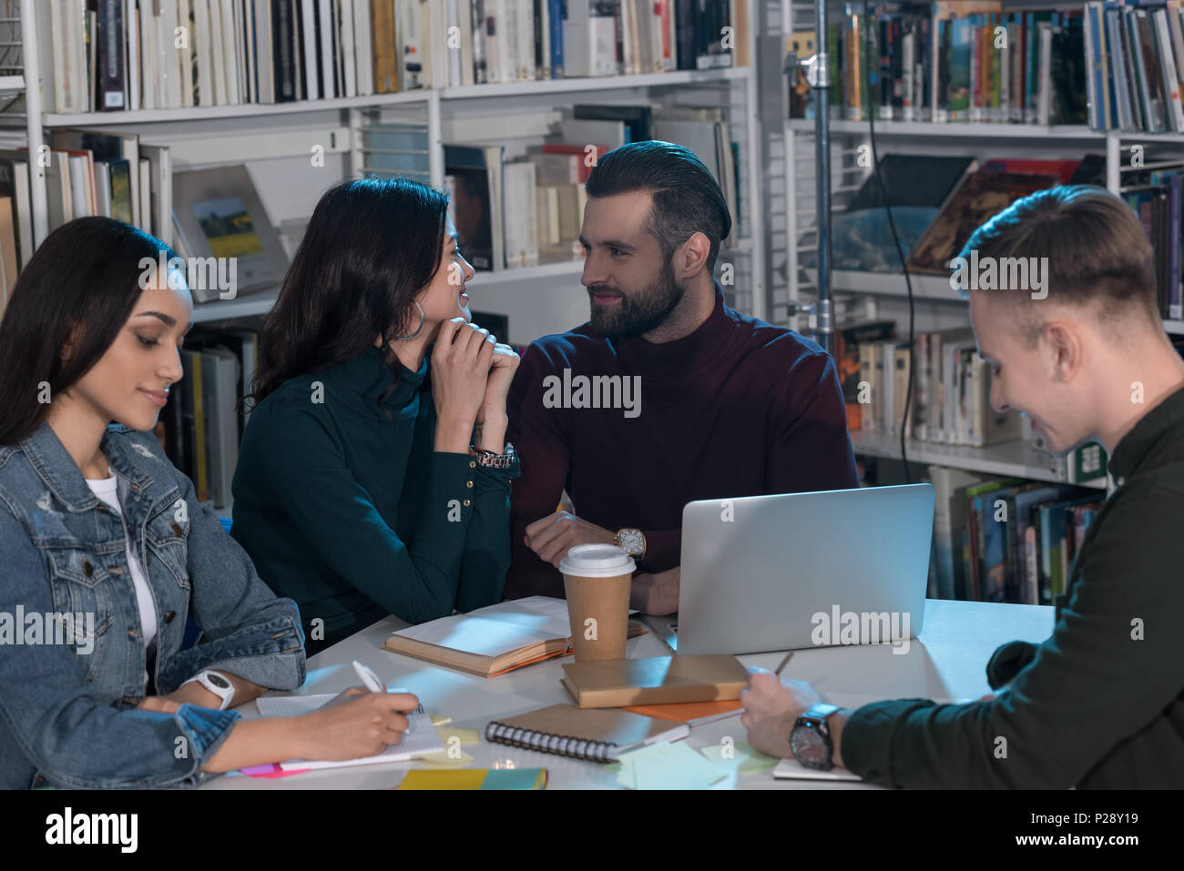 four multiethnic friends studying in library in evening Stock Photo - Alamy
