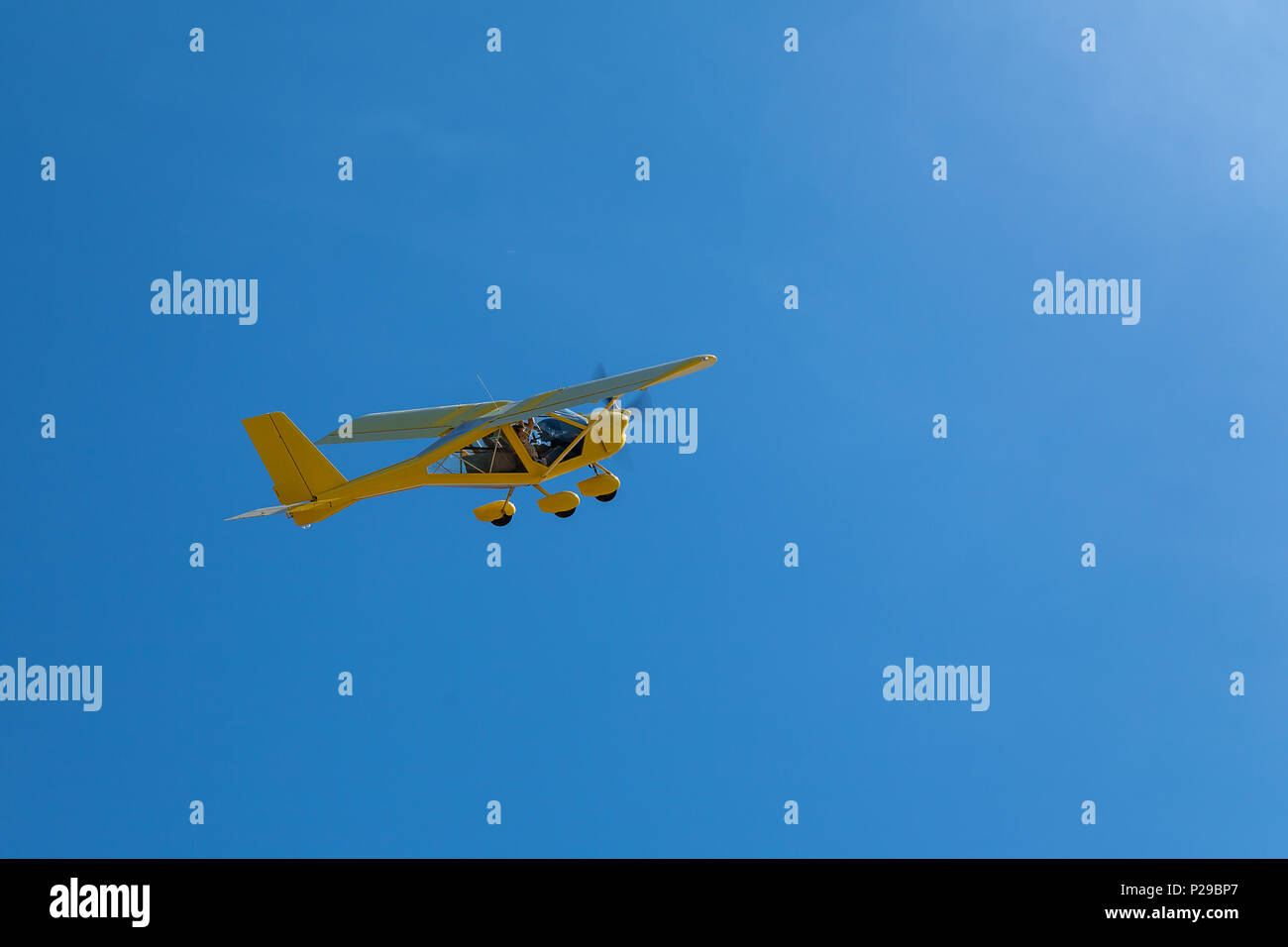 Light yellow aircraft flies in the blue sky Stock Photo - Alamy