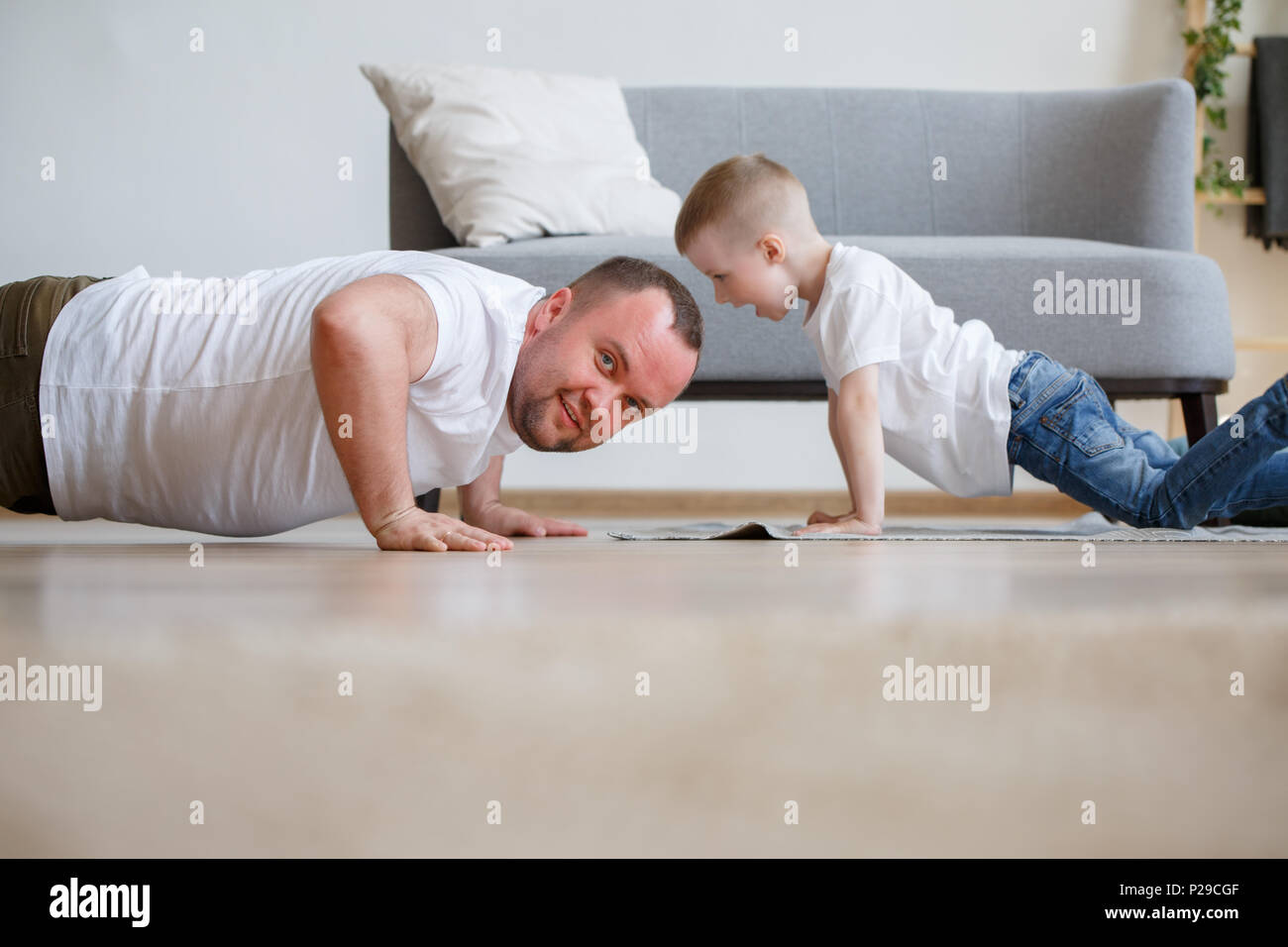 Photobook of father and son pushing on floor near sofa in apartment ...