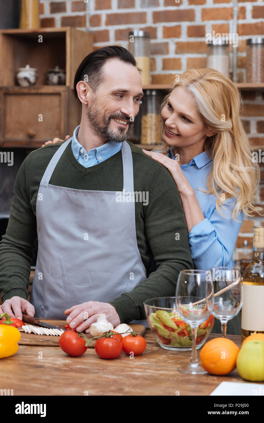 wife hugging husband while he cooking at kitchen Stock Photo - Alamy