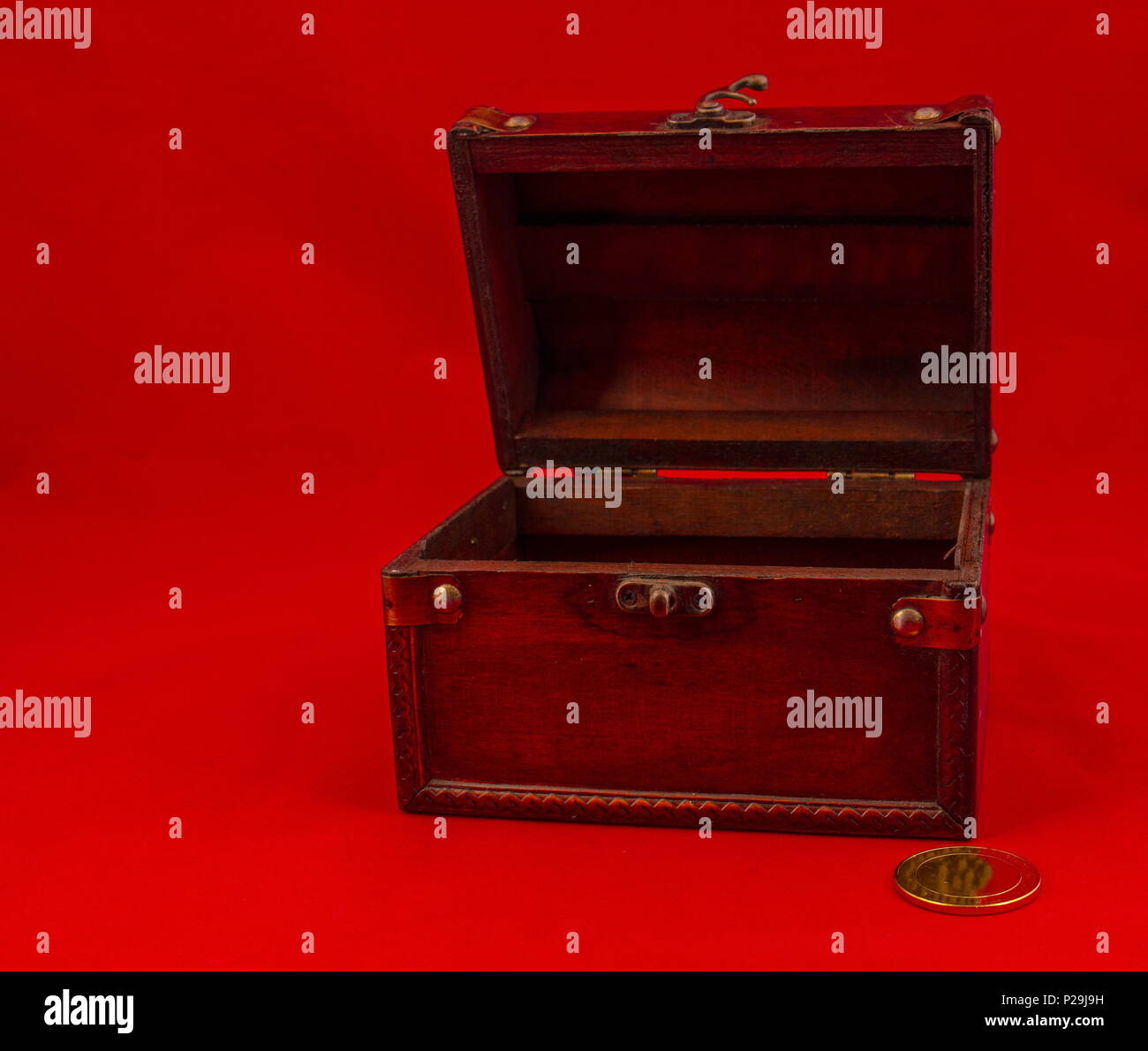 Small vintage wooden trunk with some gold coins isolated on a red ...