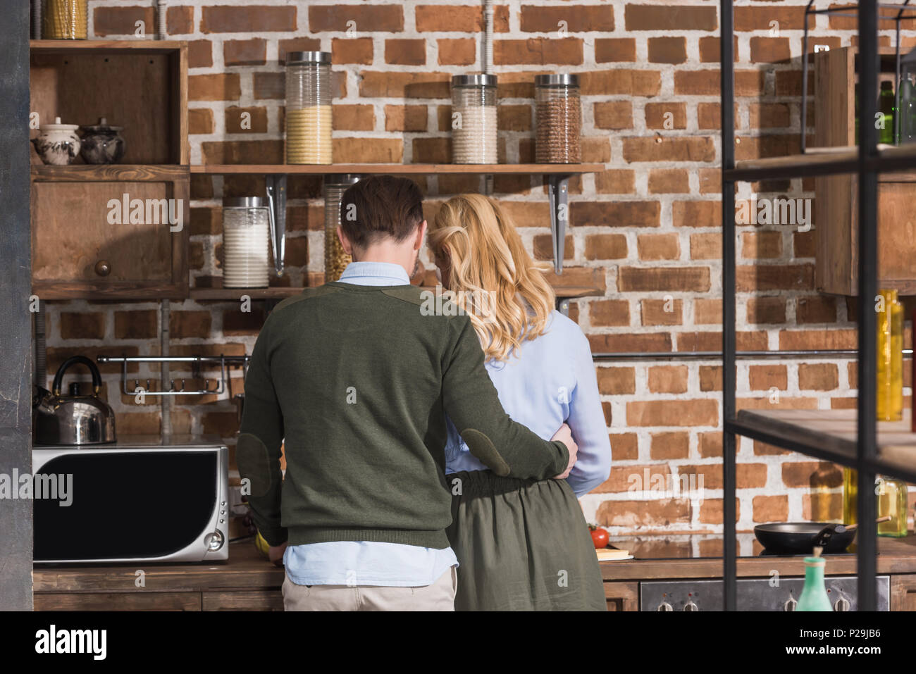 rear view of husband hugging wife at kitchen Stock Photo - Alamy