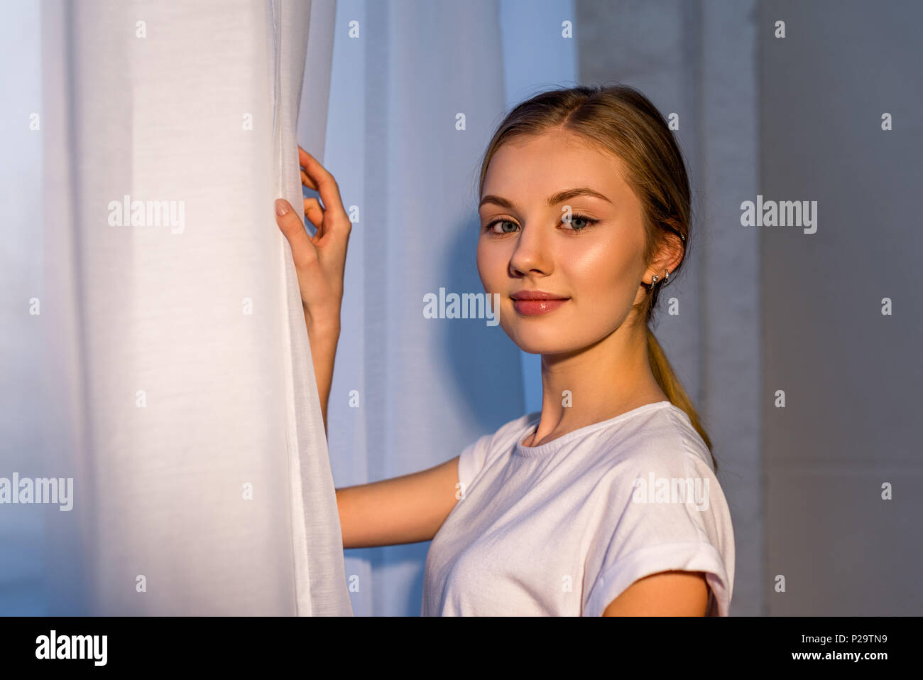 beautiful young woman standing next to window Stock Photo - Alamy