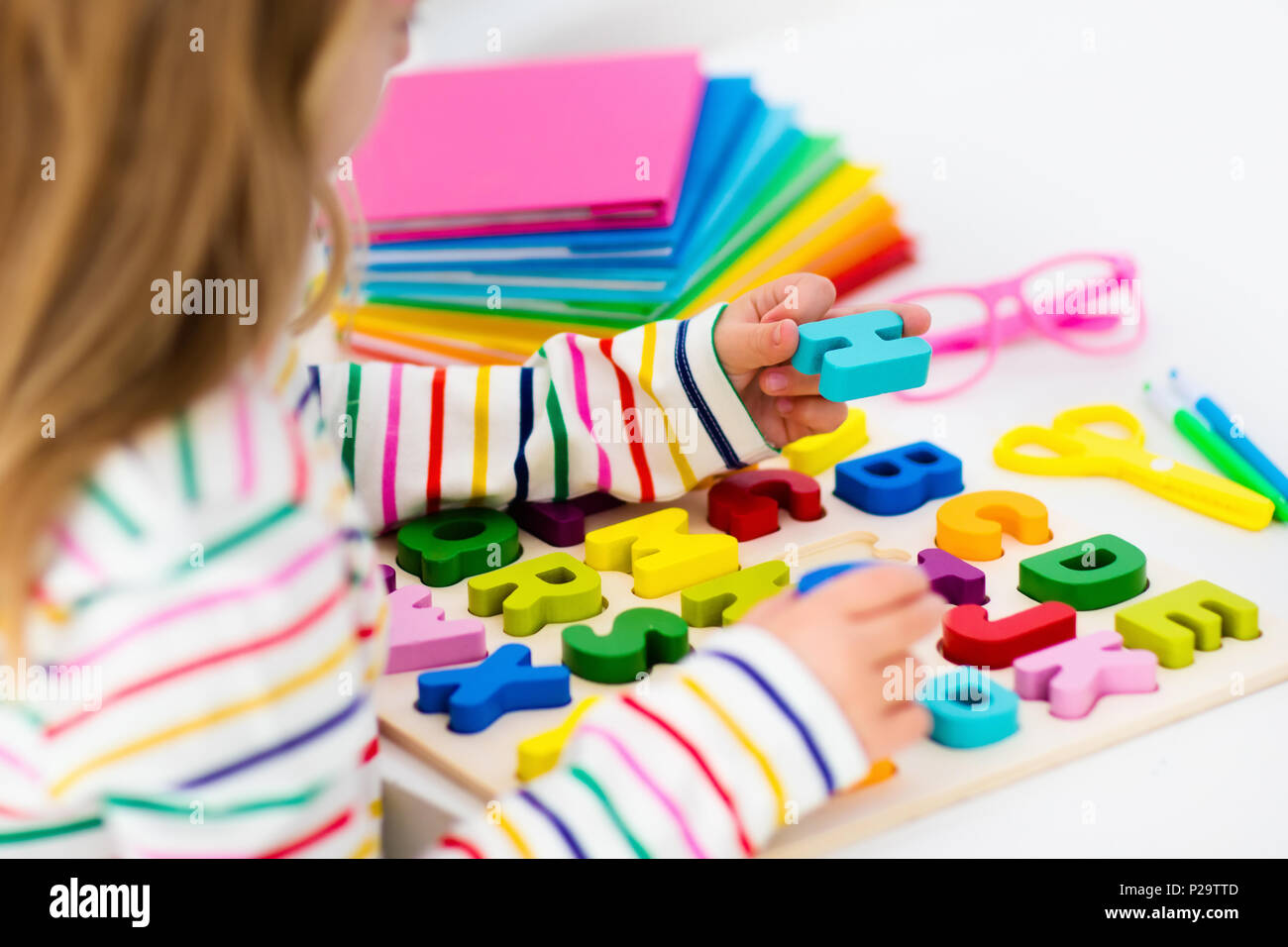 Child doing homework for school at white desk. Wooden educational abc ...