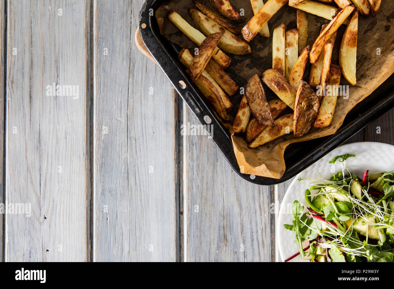 Homemade baked skin on potato fries on a rustic wooden background Stock ...