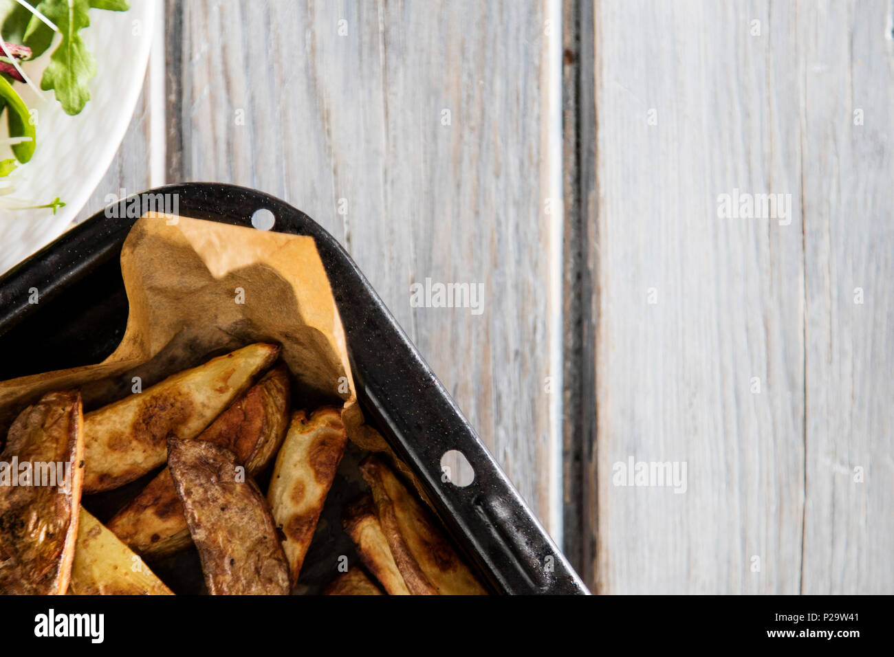 Homemade baked skin on potato fries on a rustic wooden background Stock ...