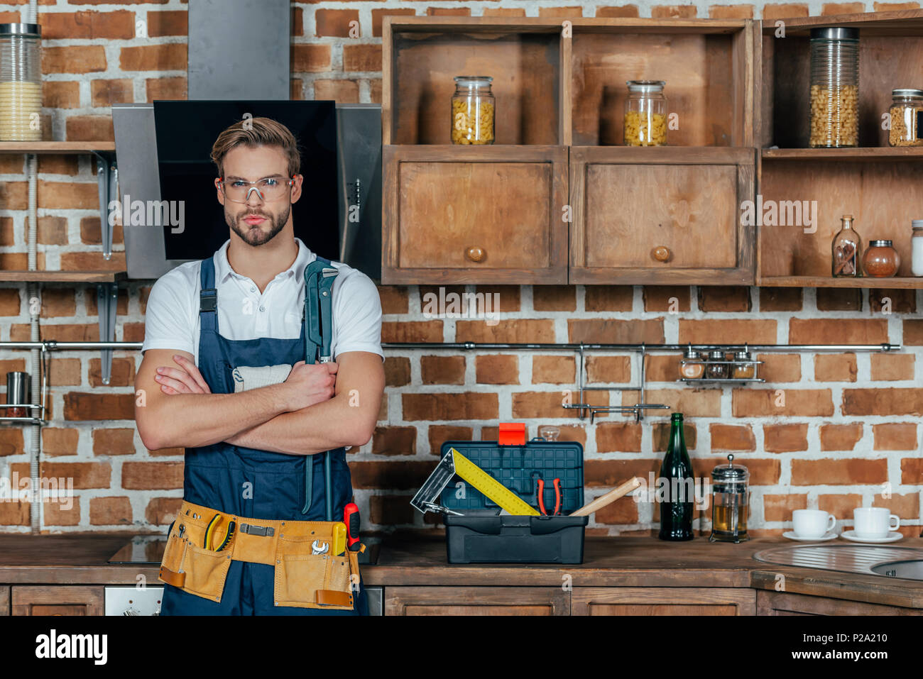 handsome young professional repairman with tool belt standing with ...