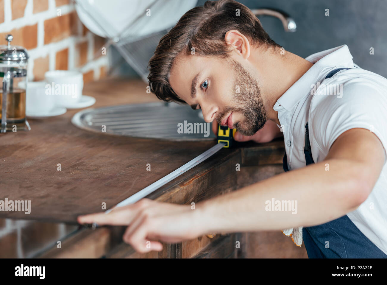 professional young handyman measuring kitchen furniture with tape Stock ...