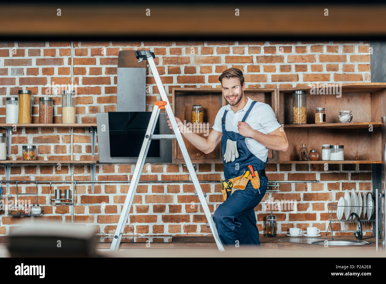 selective focus of young foreman standing on ladder and smiling at ...