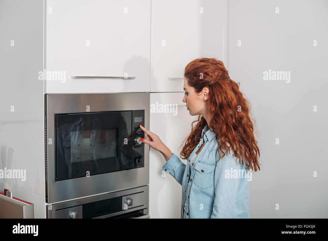 Woman turning on oven hi-res stock photography and images - Alamy