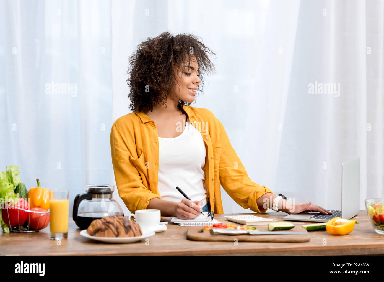 beautiful young woman working with laptop while taking meal Stock Photo ...
