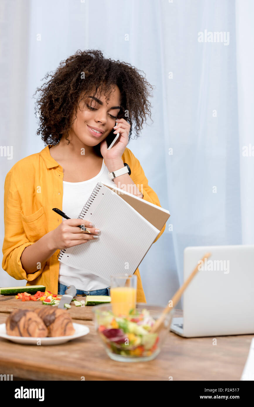 happy young woman with notebook talking by phone at home Stock Photo ...