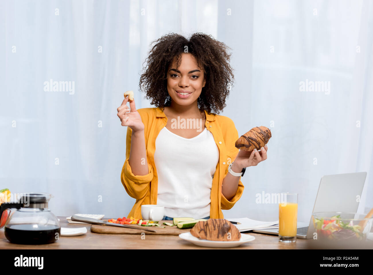 beautiful young woman eating croissant while working at home Stock ...
