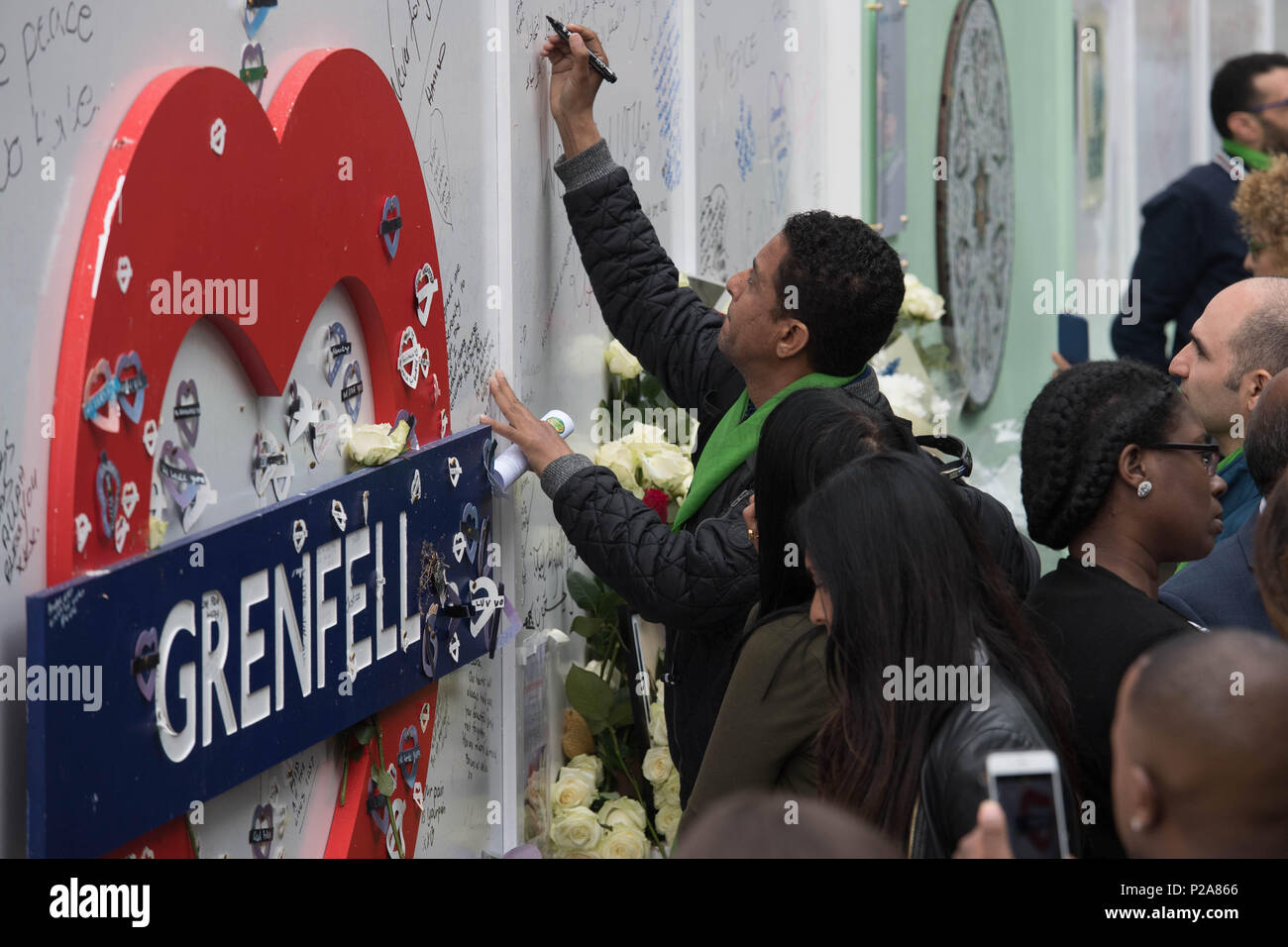 People sign a remembrance wall near the Grenfell Tower anniversary ...