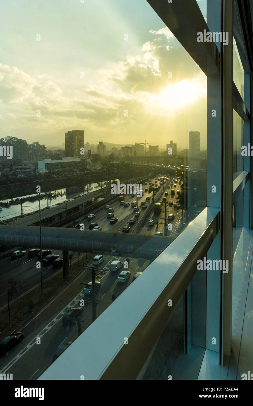 View of car traffic on avenue through corporate building window at dusk ...