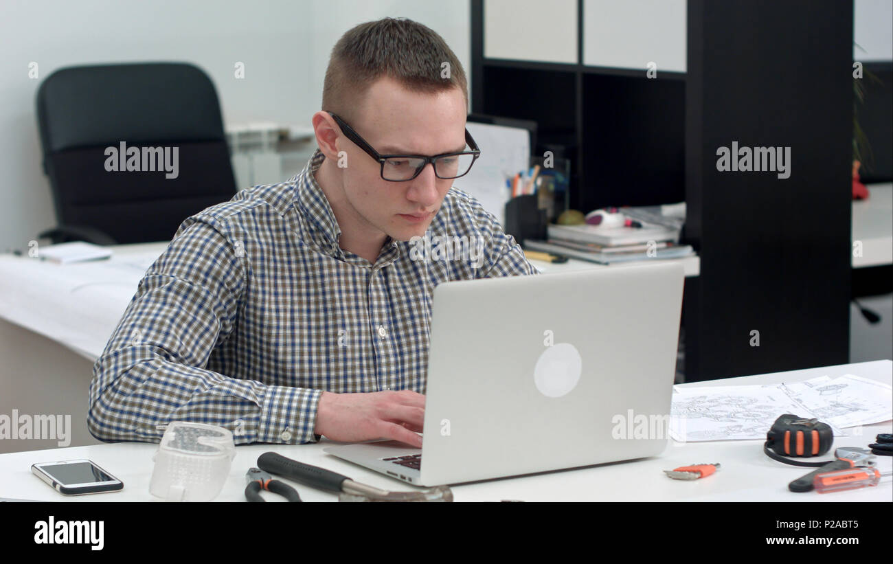 Architect in office working with blueprints and computer Stock Photo ...