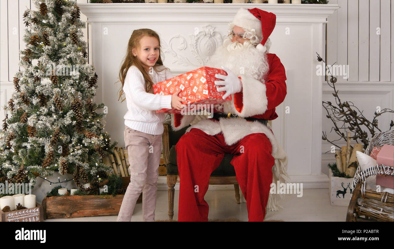 Santa Claus giving a nicely wrapped present to a cute little girl Stock ...