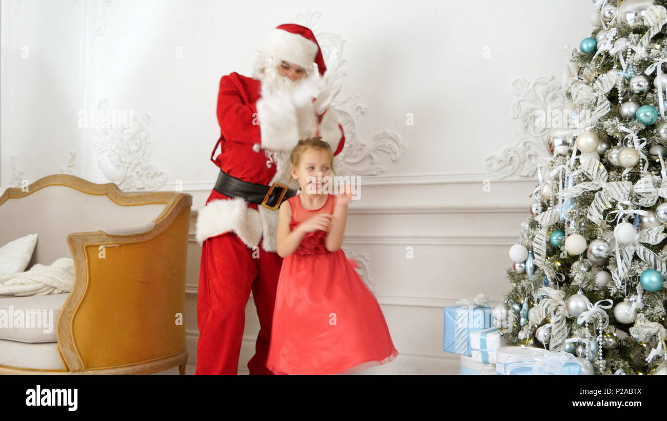 Santa Claus clapping his hands while pretty little girl dancing around ...