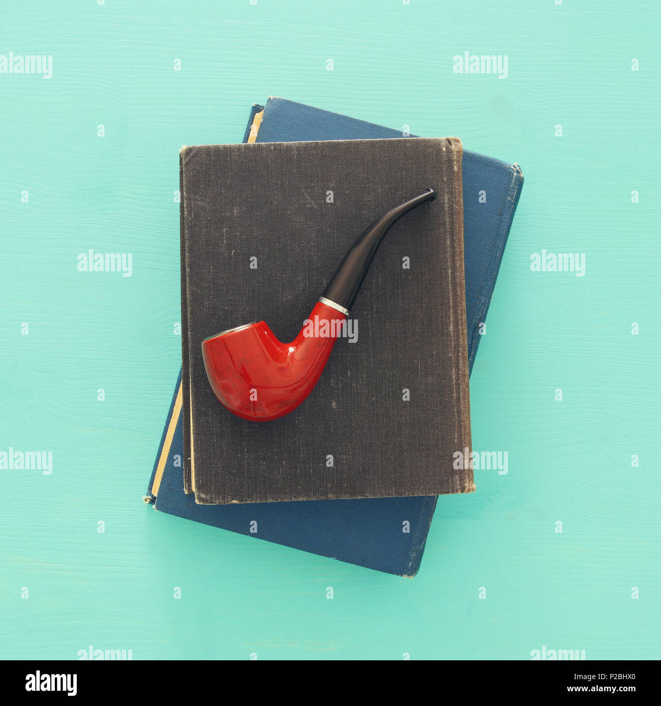 Top view of old smoking pipe and vintage books over blue background ...