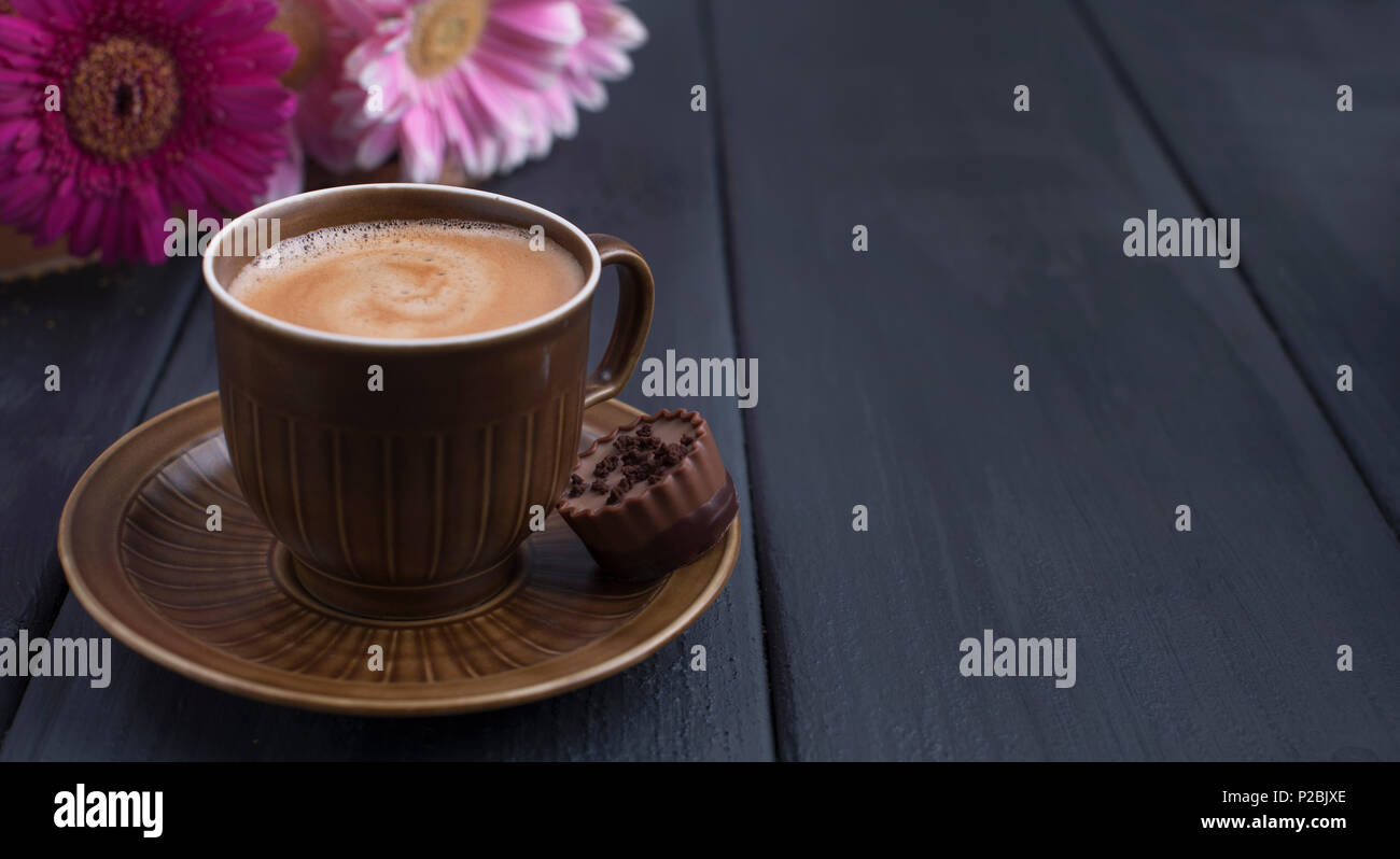 Delicious milk chocolate, a bouquet of fresh flowers and a morning aromatic coffee. Black wooden ...