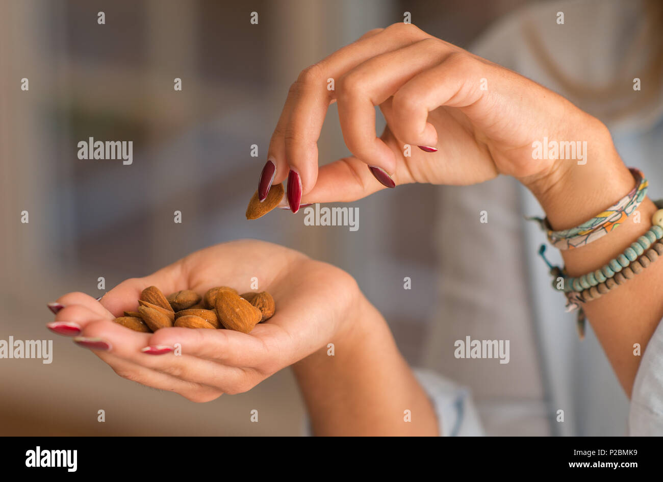 Young woman hands holding nuts at the kitchen. Close up. Healthy ...