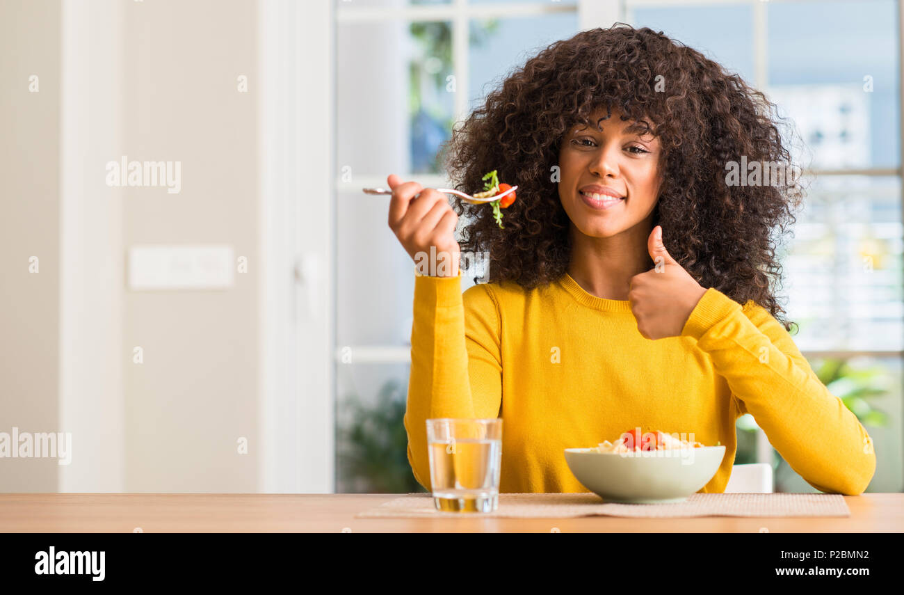 African american woman eating pasta salad at home happy with big smile ...