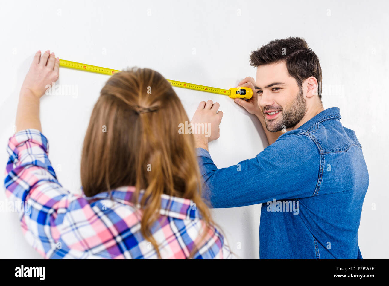girlfriend and boyfriend measuring wall with tape measure Stock Photo ...