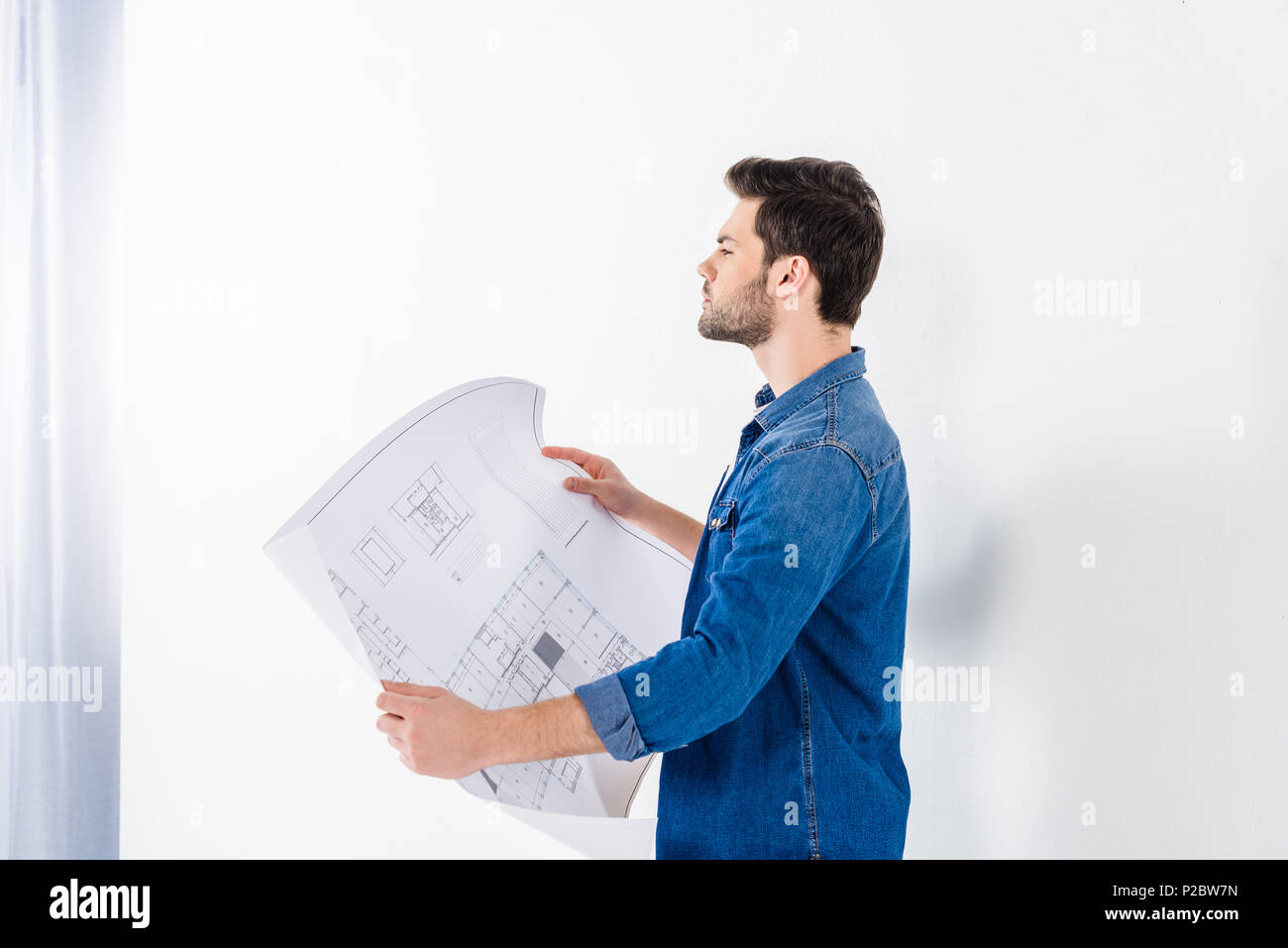 handsome architect holding blueprint and looking away Stock Photo - Alamy